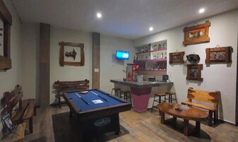 Mesa de bilhar, área de bar e assentos em um salão.
