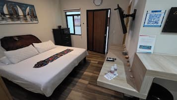 Quarto de hotel com uma cama, uma escrivaninha, um relógio e um quadro na parede.