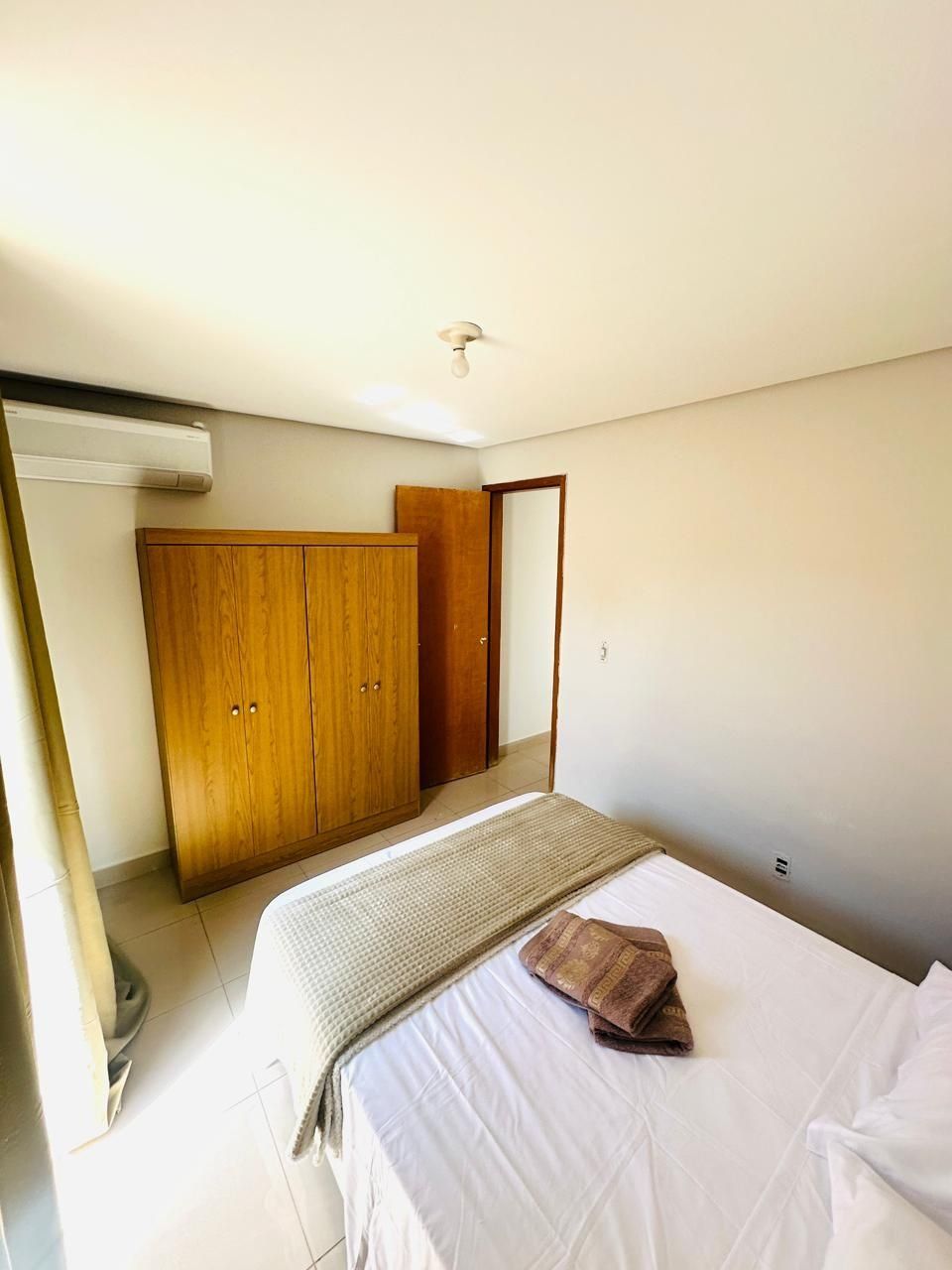 Um quarto com cama, guarda-roupa de madeira e ventilador de teto.