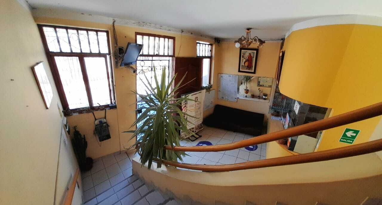 Escadaria que leva a uma sala de estar com sofá, televisão e uma planta.