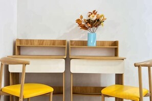Área de estar com duas cadeiras e uma mesa pequena com um vaso de flores.