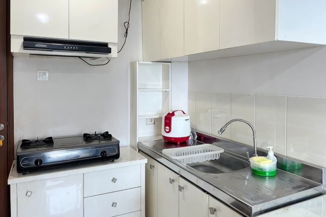 Cozinha com fogão a gás, chaleira, pia e escorredor de louça.