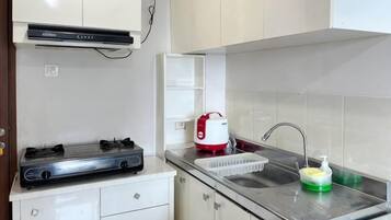 Cozinha com fogão a gás, chaleira, pia e escorredor de louça.