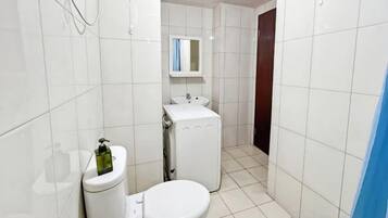 Um banheiro pequeno com azulejos, vaso sanitário, pia e espelho.