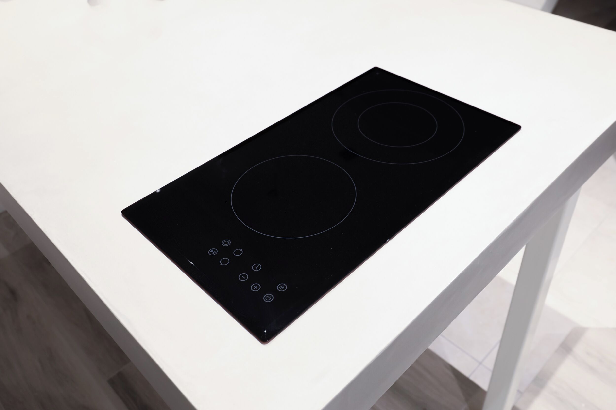 Uma cozinha moderna com uma placa de indução preta e bancada branca.