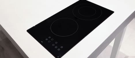 Uma cozinha moderna com uma placa de indução preta e bancada branca.