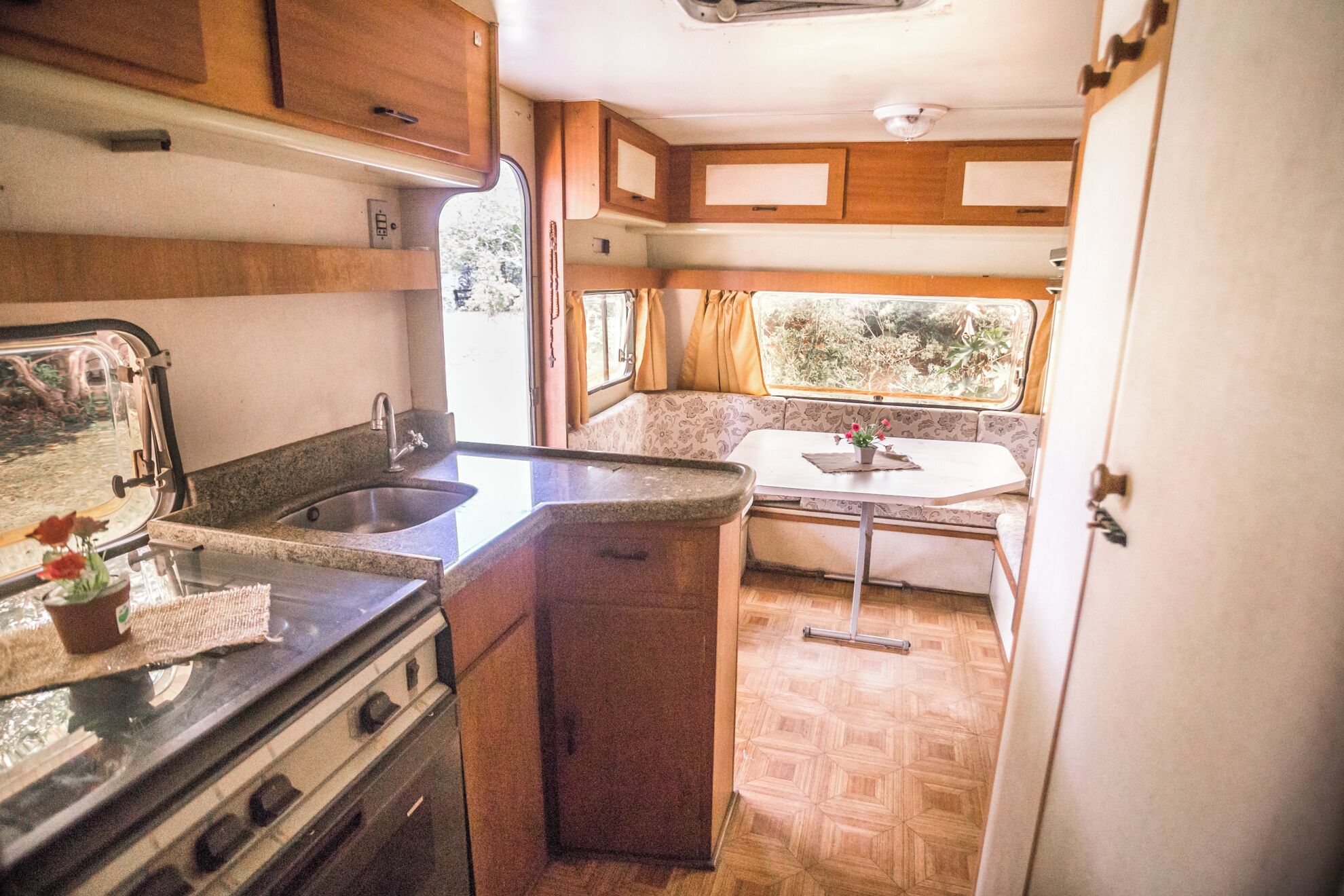 Cozinha compacta de RV com pia, fogão e um pequeno espaço para refeições.