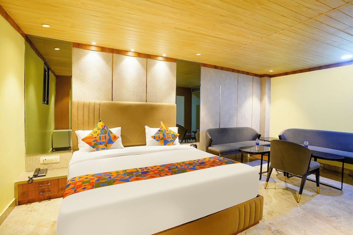 Quarto de hotel com uma cama grande, um sofá, uma mesinha e uma cadeira.