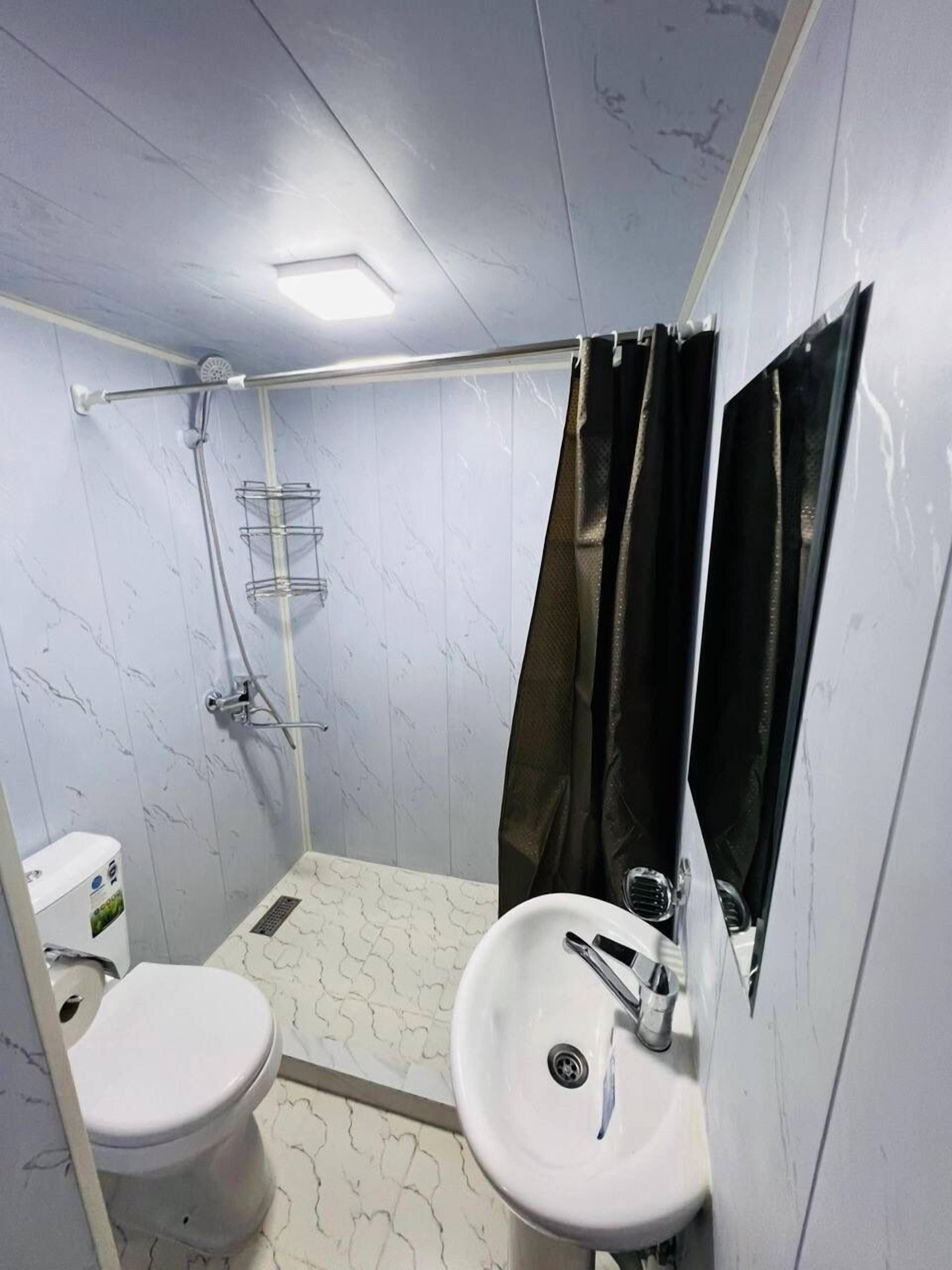 Uma casa de banho pequena com sanita, lavatório, chuveiro e um porta-toalhas.