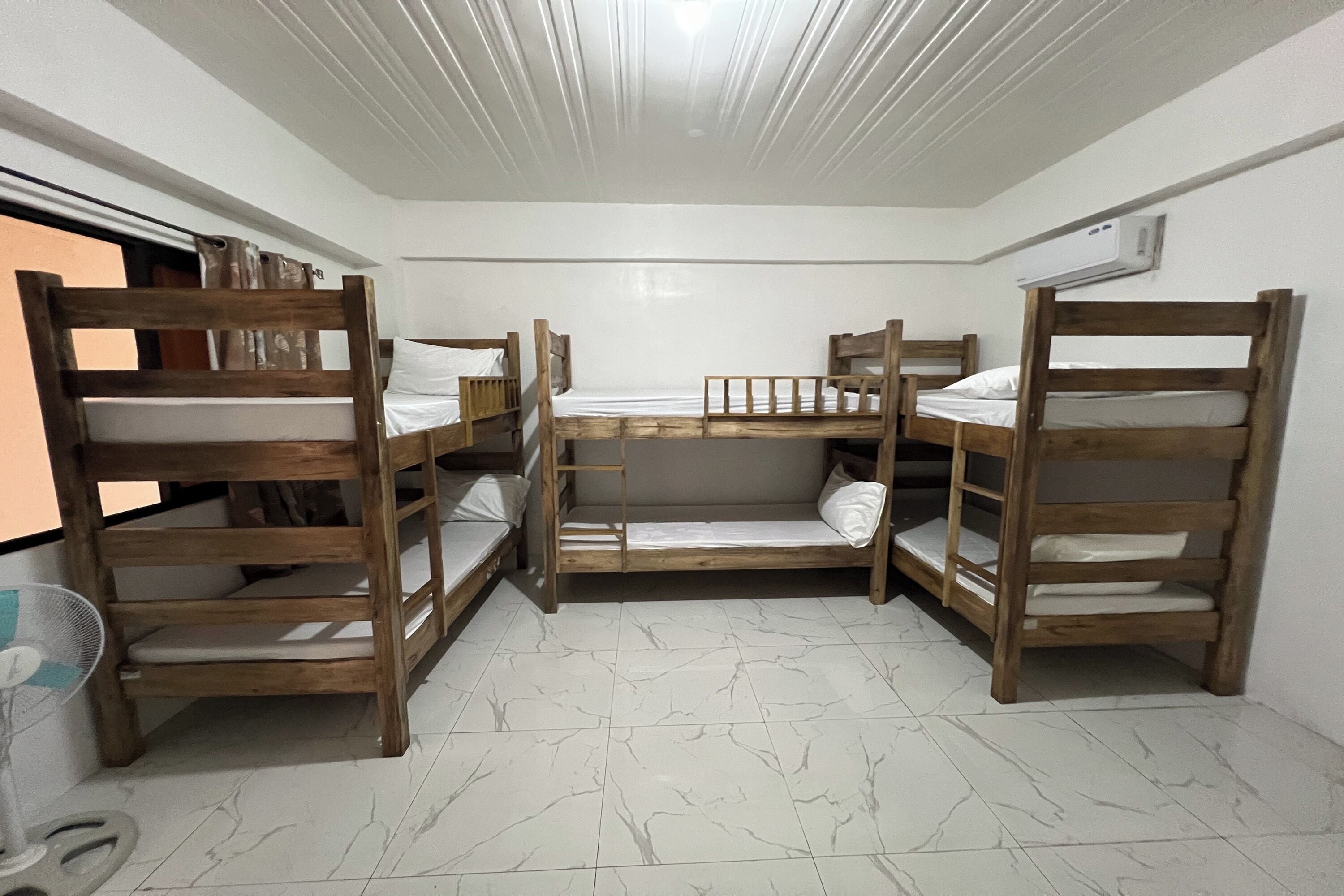 Quarto com beliches, ventilador de teto e ar condicionado.