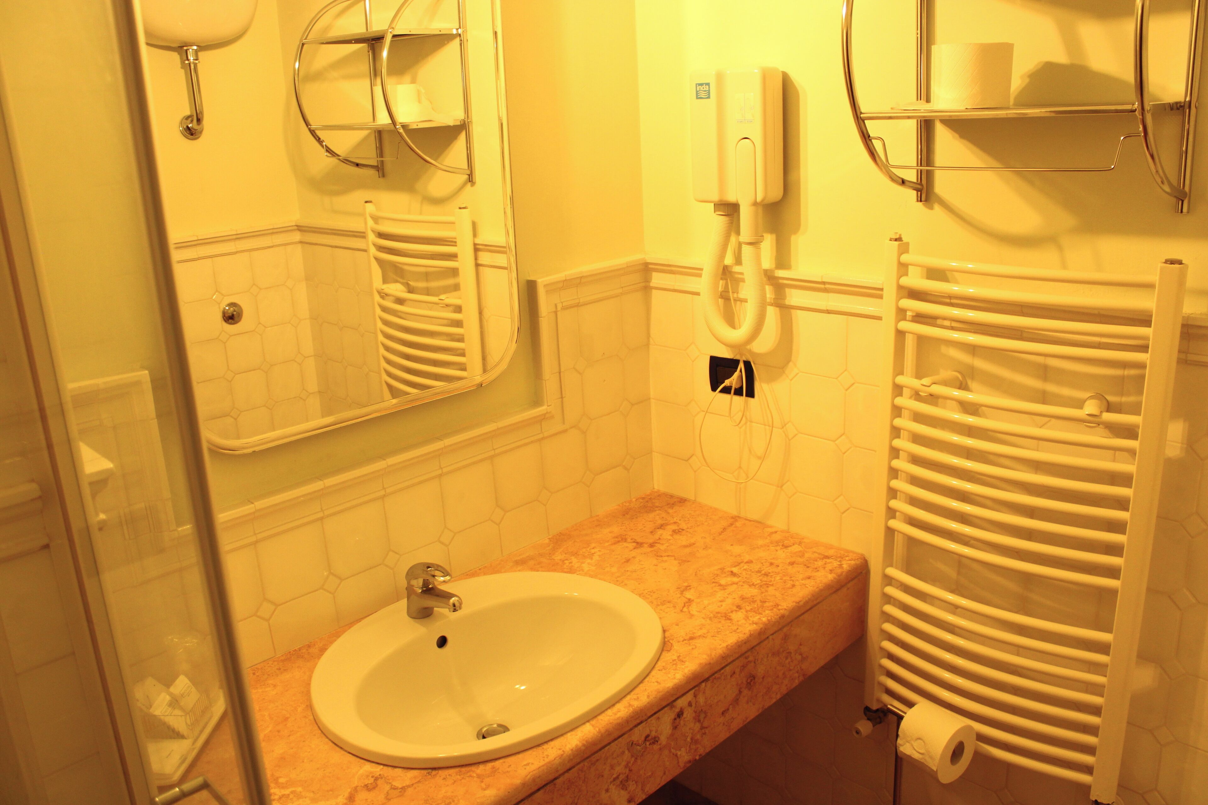 Casa de banho com lavatório, espelho, toalheiro e suporte para papel higiénico.