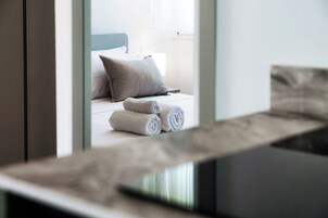 Quarto de hotel moderno com cama, almofadas e toalhas enroladas.
