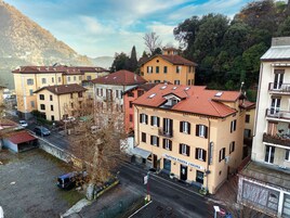 Um edifício de vários andares com pizzaria no andar térreo, cercado por outros edifícios e uma paisagem montanhosa.