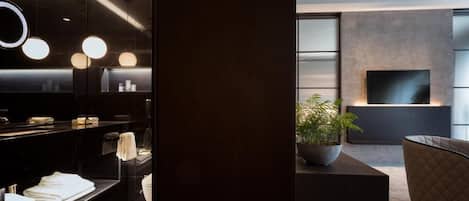 Uma casa de banho moderna com esquema de cores escuras, um lavatório e um espelho.