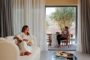 Quarto com sofá, mesa de jantar e vista para o exterior.