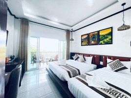 Quarto de hotel com duas camas, uma escrivaninha e uma varanda.