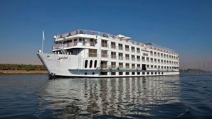 Um grande cruzeiro fluvial de vários andares, com varandas e uma bandeira.
