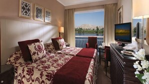 Quarto de hotel com duas camas, televisão, escrivaninha e varanda com vista.