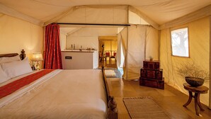 Um quarto com tenda, uma cama grande, uma escrivaninha pequena e uma janela.