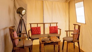 Um quarto com tenda, mobiliado com madeira, incluindo cadeiras e uma mesa, e um abajur.