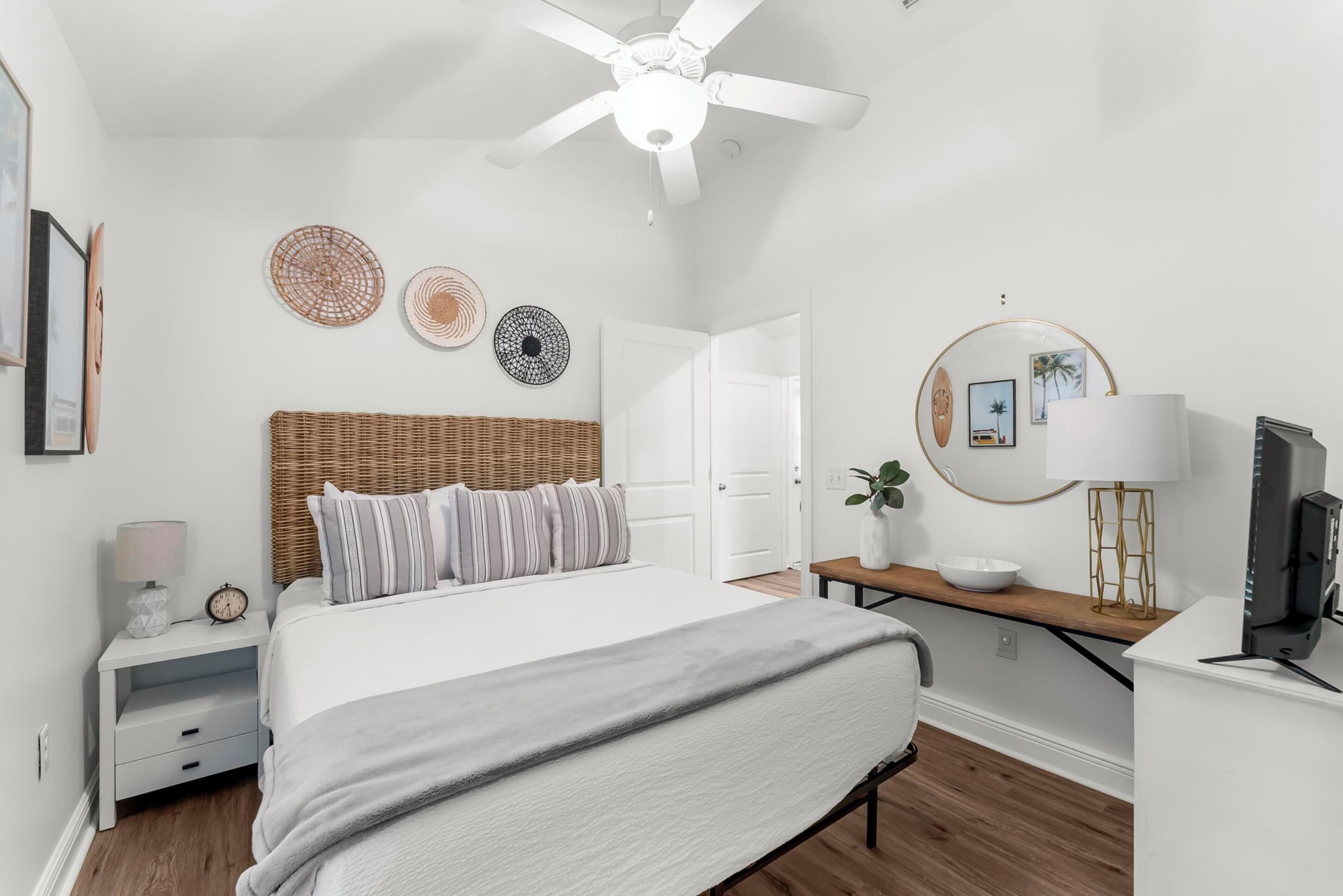 Quarto com cama, mesa de cabeceira e ventoinha no teto.