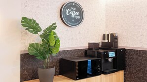 Uma estação de café com uma planta grande, uma máquina de café e uma placa que diz “Somos apaixonados por café.”