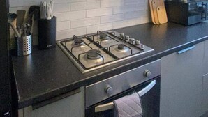 Uma cozinha moderna com fogão a gás, armários pretos e coifa de aço inoxidável.