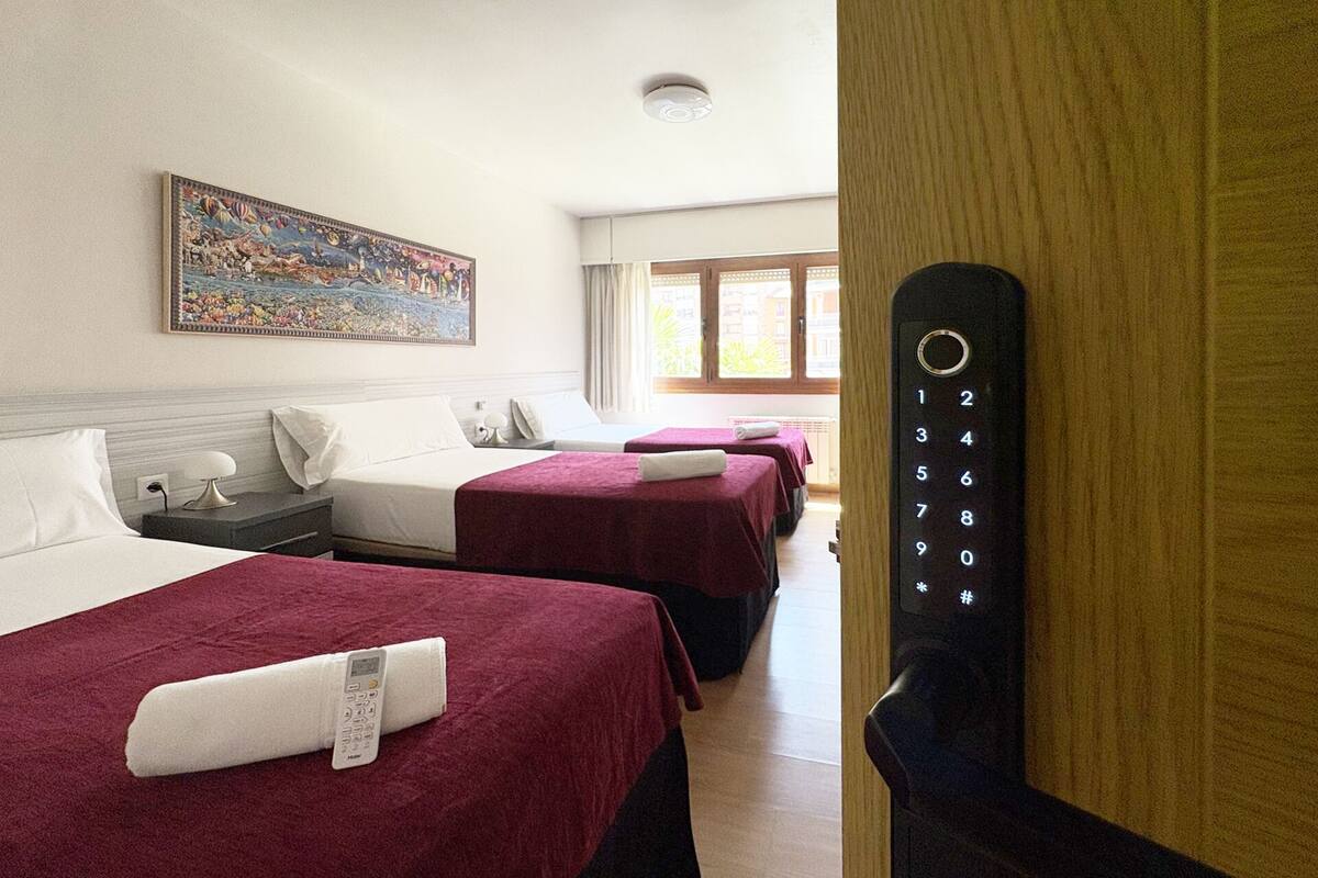Quarto de hotel com duas camas, um quadro na parede e um teclado na porta.