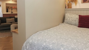 Quarto com cama, sofá, mesa pequena e prateleira na parede.