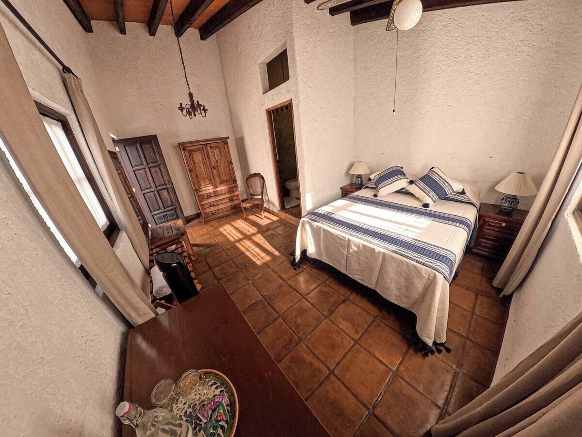 Um quarto com uma cama, mobiliário de madeira e piso de azulejos.