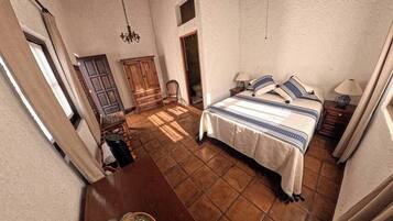 Um quarto com uma cama, mobiliário de madeira e piso de azulejos.