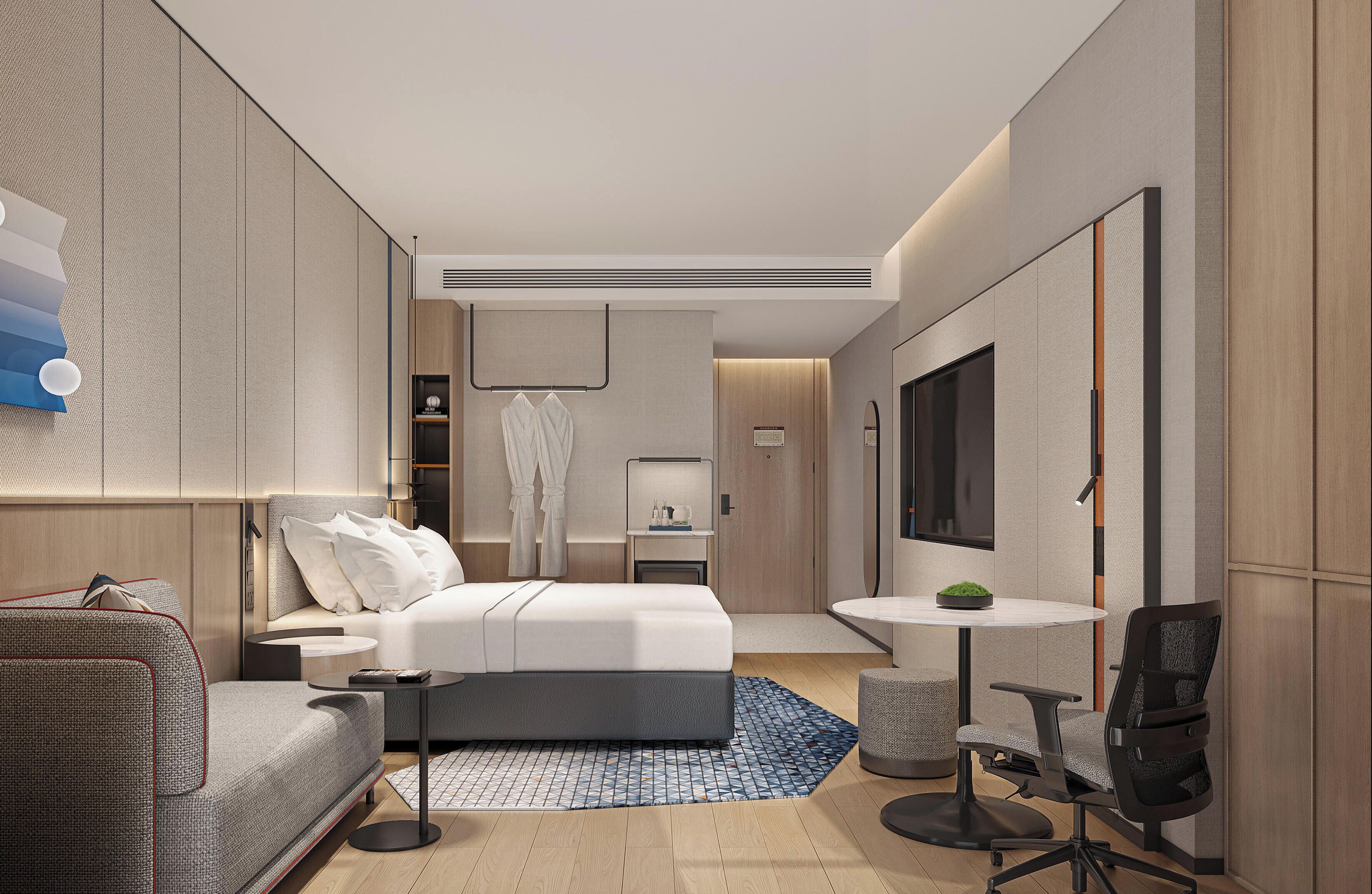 Quarto de hotel moderno com cama, área de estar, TV e uma pequena mesa.