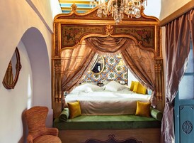 Quarto com cama grande, dossel decorativo, espelho e lustre.