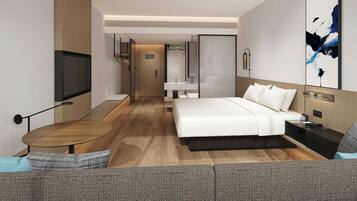 Quarto de hotel moderno com uma cama grande, um sofá, uma TV e um banheiro visível através de uma porta aberta.