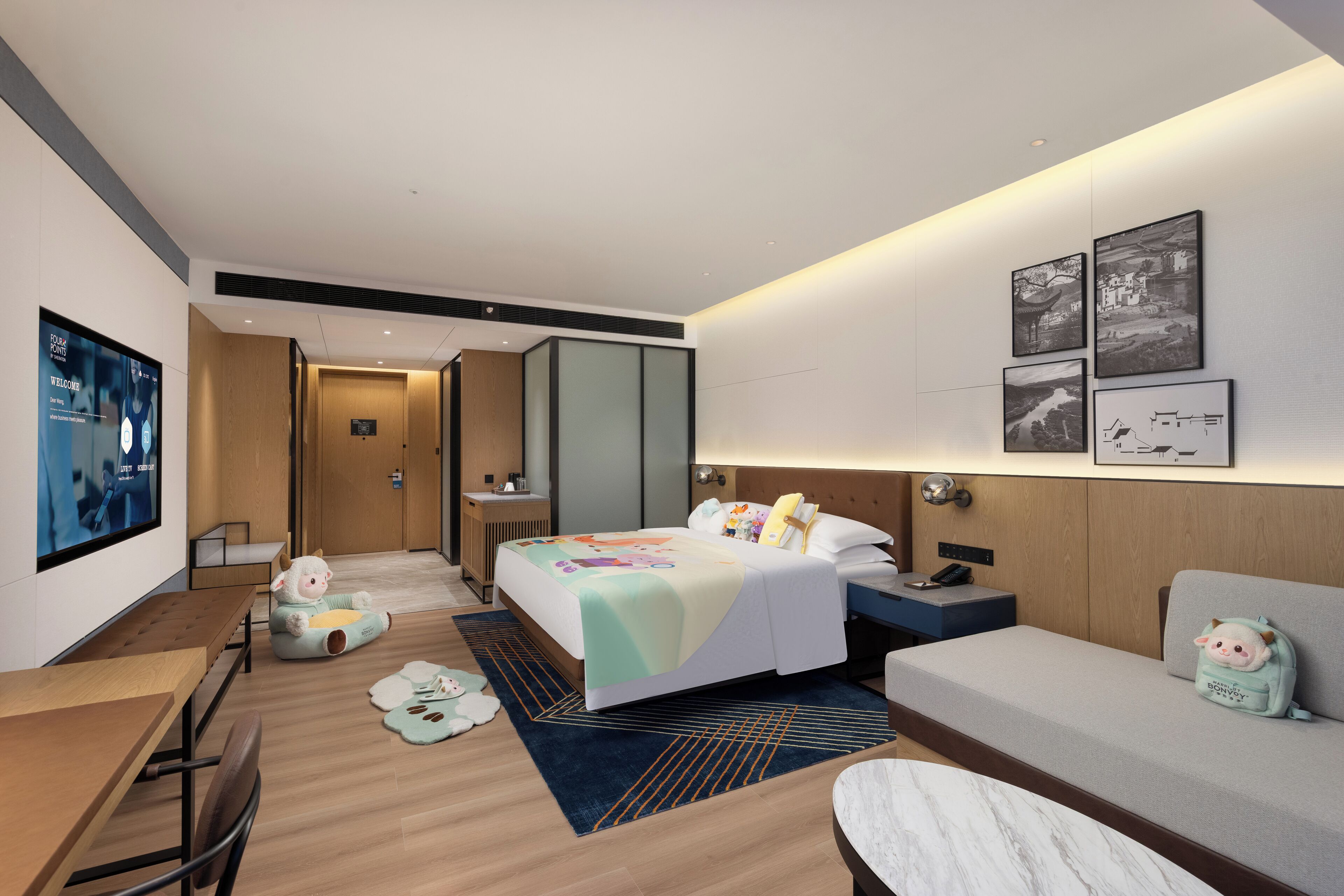 Quarto de hotel moderno com uma cama grande, um sofá, uma escrivaninha e uma televisão.