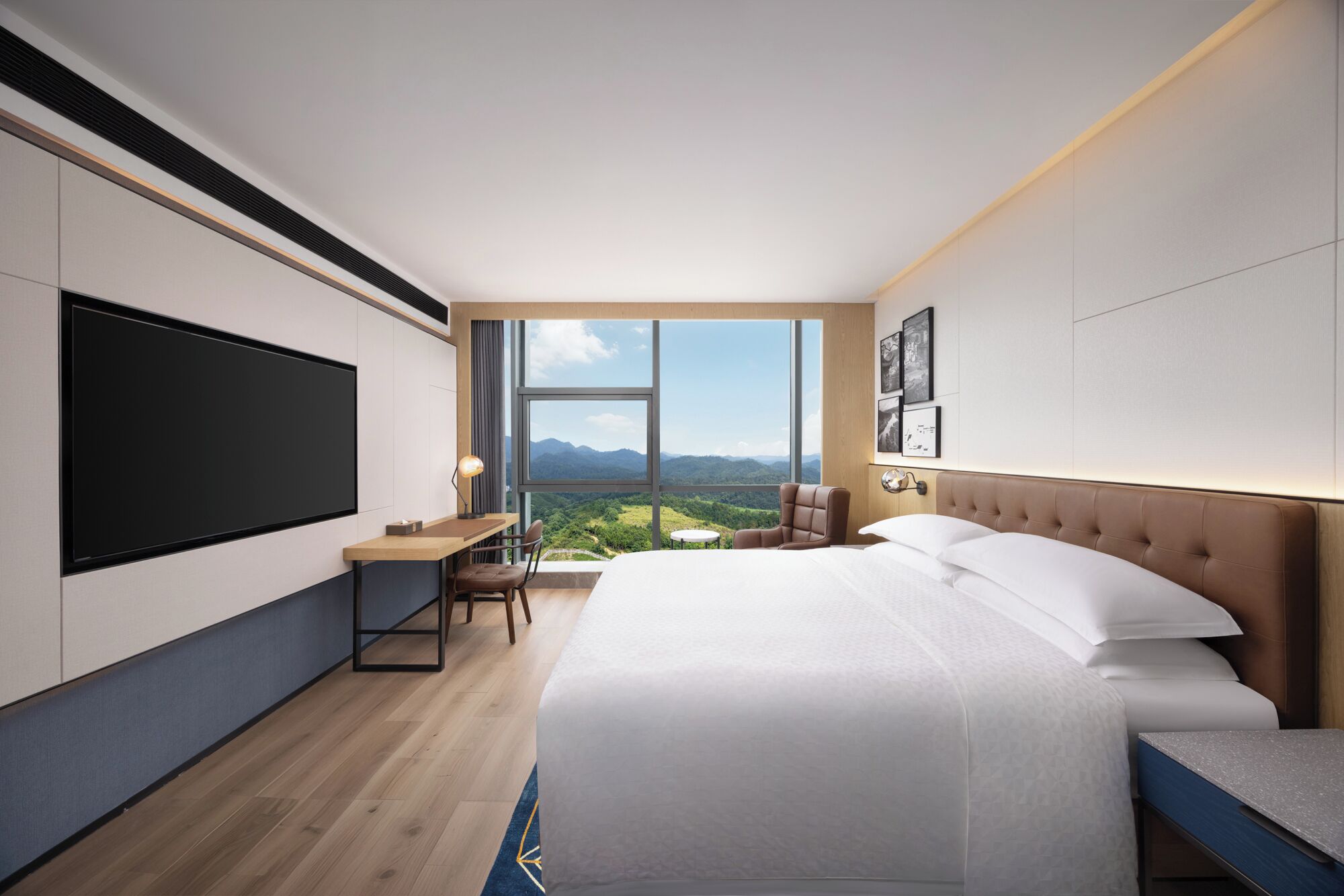 Quarto de hotel moderno com uma cama grande, uma escrivaninha e uma televisão.