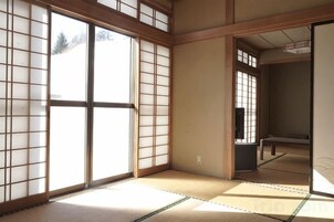 Um quarto japonês tradicional com tatames, portas deslizantes e vista para o exterior.