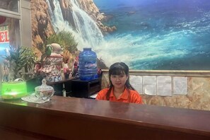 Balcão de recepção com um mural de cachoeira, um bebedouro e um recipiente de vidro.