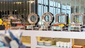 Uma mesa de buffet com vários pontos de serviço e uma grande variedade de pratos.