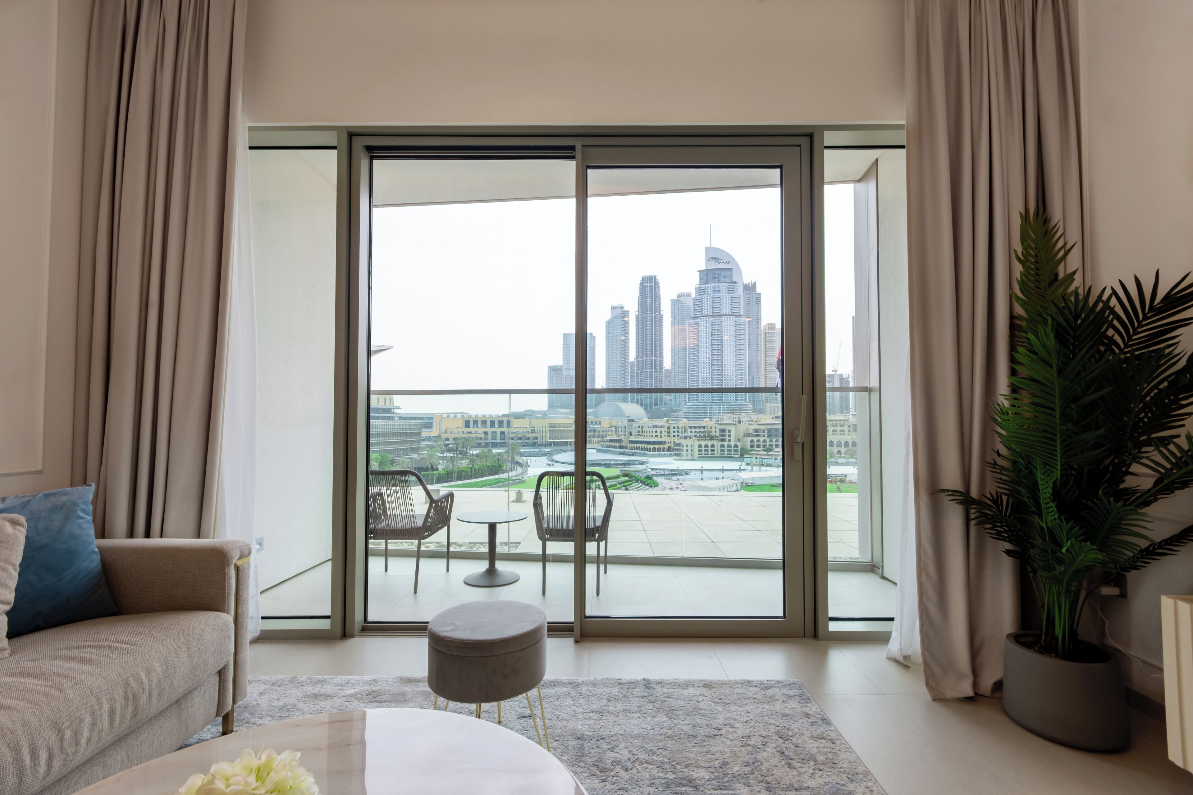 Uma sala de estar moderna com um sofá, uma mesa de centro e vista para o horizonte urbano através de amplas portas de vidro.