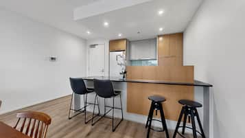 Uma cozinha moderna com uma ilha central, banquetas e uma área de refeições com uma mesa e cadeiras de madeira.