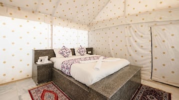 Quarto em estilo de tenda, com cama, mesas de cabeceira e tapetes estampados.