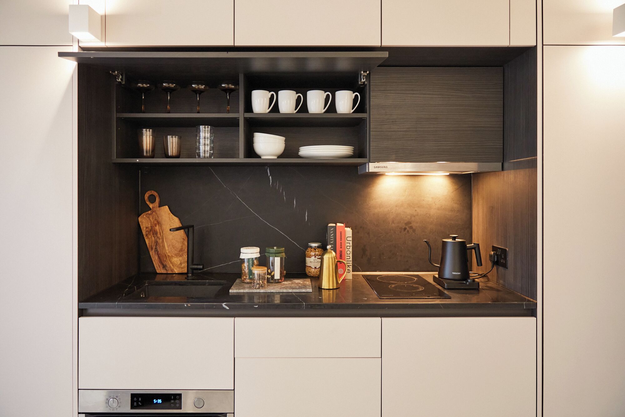 Uma cozinha moderna com forno embutido, máquina de café e diversos utensílios de cozinha.