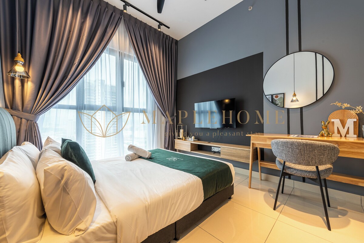 Quarto de hotel moderno com uma cama, uma escrivaninha, uma cadeira, uma TV e uma janela grande com cortinas.