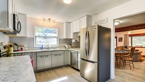 Uma cozinha moderna com geladeira embutida, uma janela e um espaço de refeições com mesa e cadeiras de madeira.