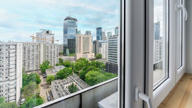 Um apartamento alto com vista para um horizonte urbano, incluindo edifícios modernos e uma grua de construção.