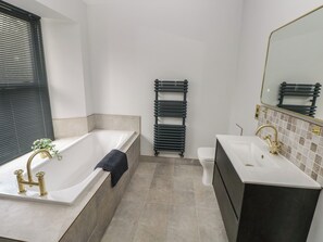 Uma casa de banho moderna com uma banheira independente, um lavatório e uma sanita.