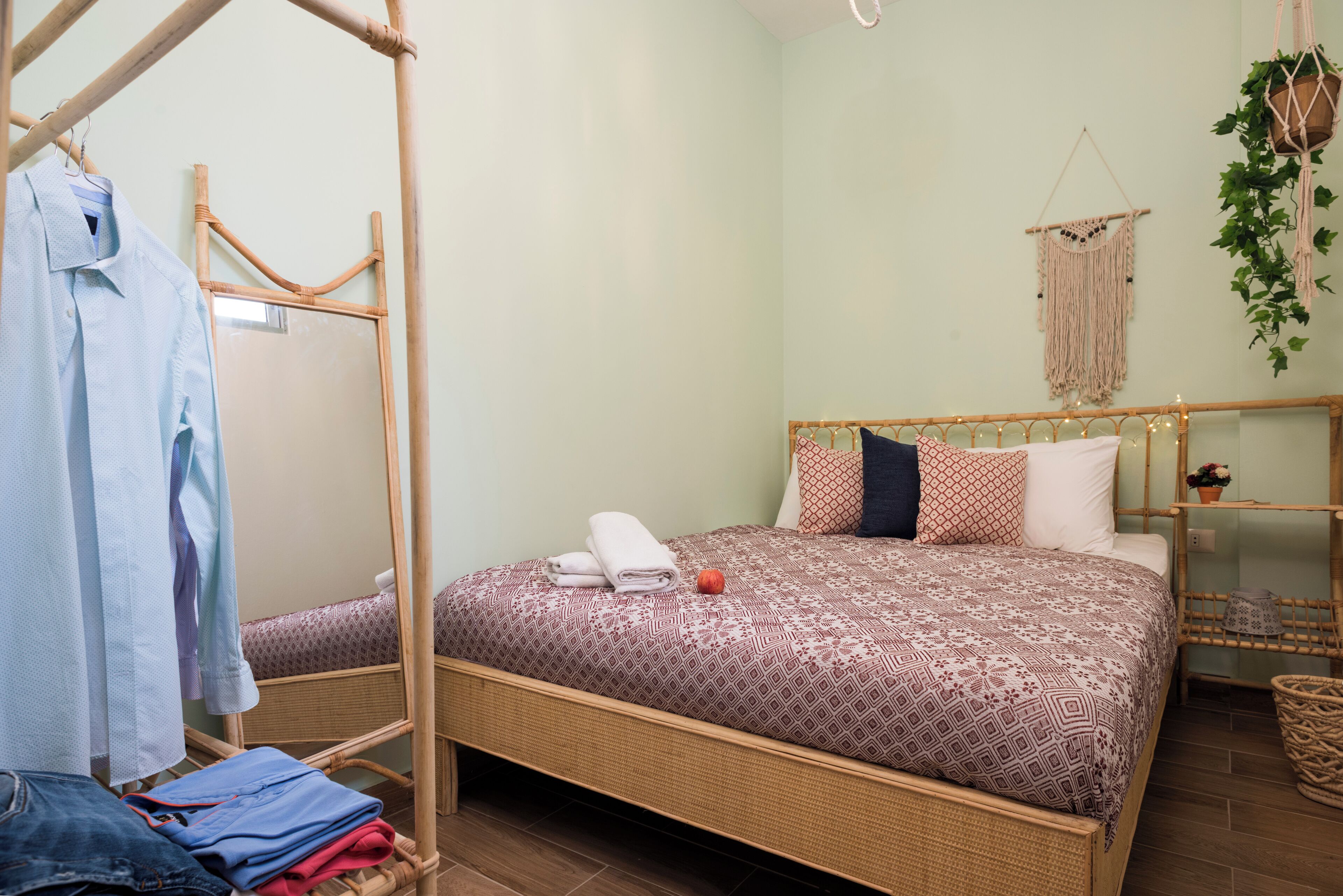 Quarto com cama, cadeira suspensa, guarda-roupa e um painel de macramé na parede.