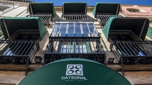 Um hotel com toldo verde, várias varandas e vista clara do céu.