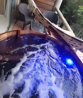 Uma banheira de hidromassagem com borda de madeira e divisória de vidro.